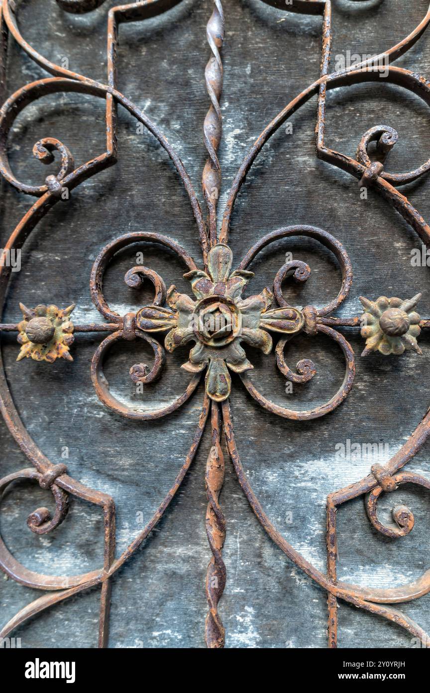 An intricately designed wrought iron gate features floral motifs and a ...