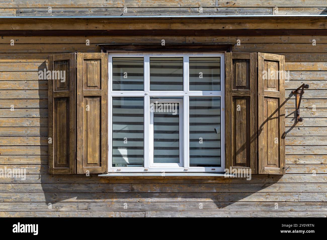 The wooden shutters of a window are wide open, revealing a bright ...