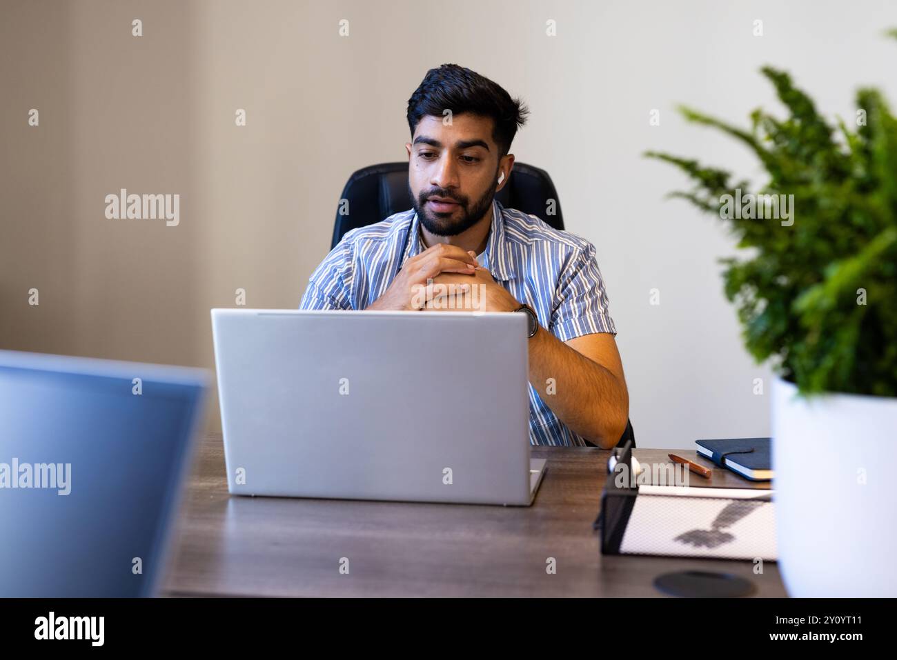 Working in office, Indian man using laptop and participating in video ...