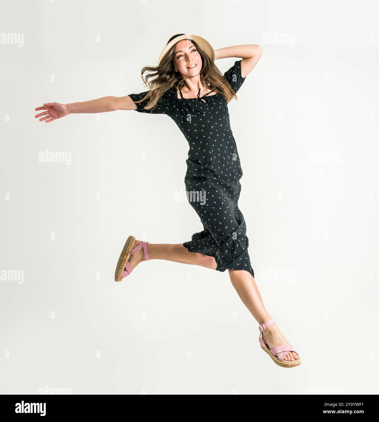 Young woman jumping in studio wearing hat Stock Photo - Alamy