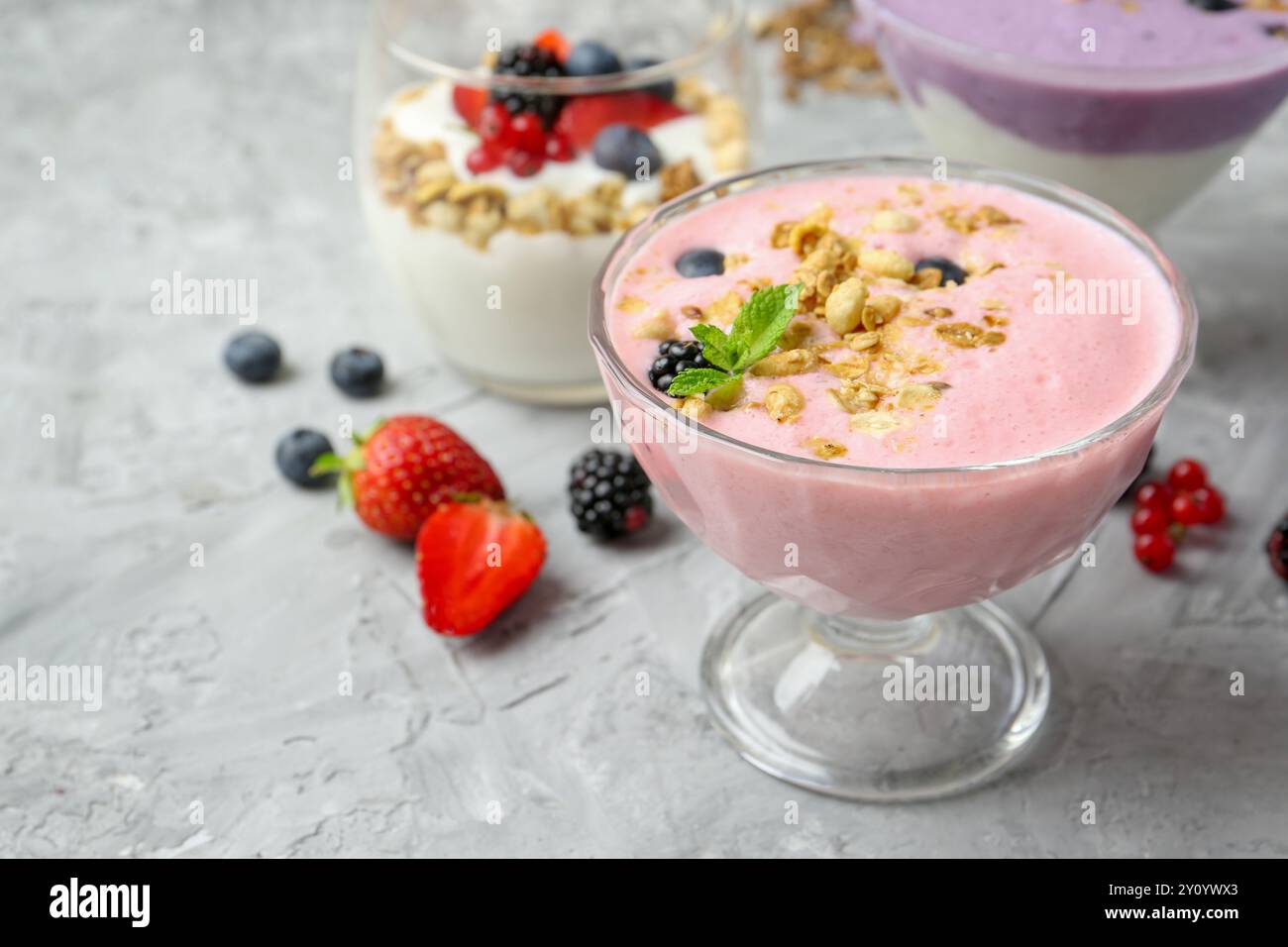 Different tasty yogurts with fresh berries and granola in glass dessert ...
