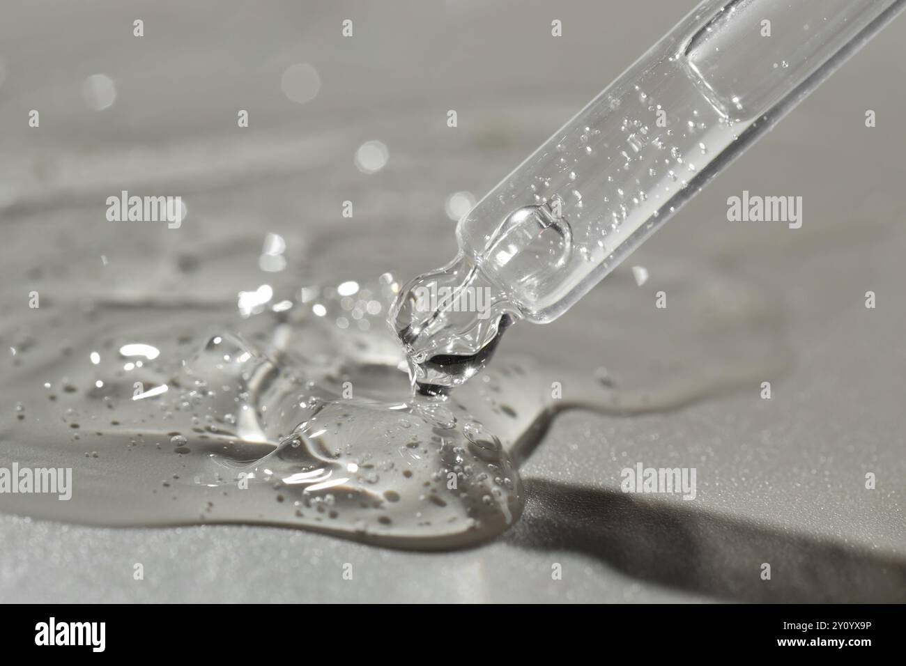 Dripping cosmetic serum from pipette on grey background, closeup Stock ...