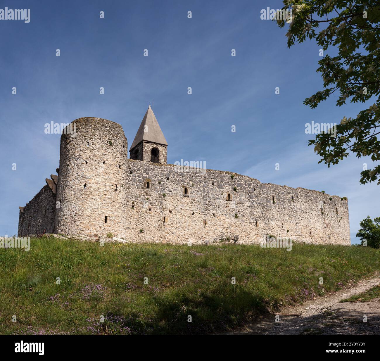 View of an old medieval church surrounded by a tall stone wall and a ...