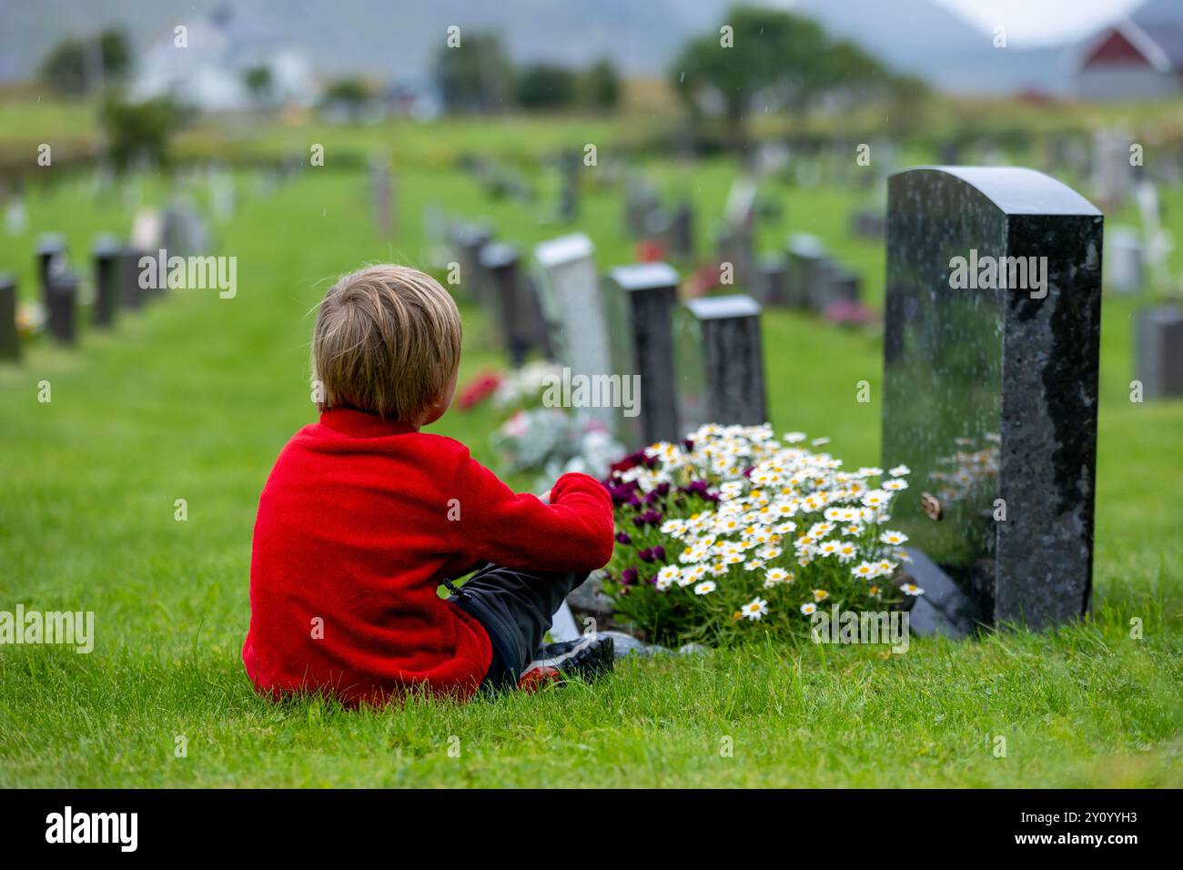 Sad little child, blond boy, standing in the rain on cemetery, sad ...