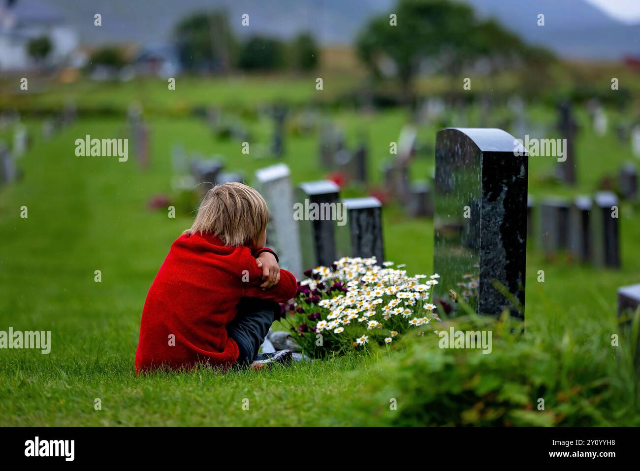 Sad little child, blond boy, standing in the rain on cemetery, sad ...