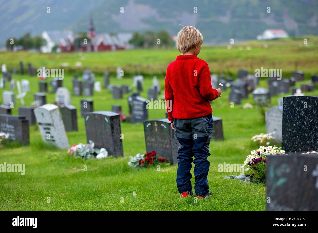 Sad little child, blond boy, standing in the rain on cemetery, sad ...