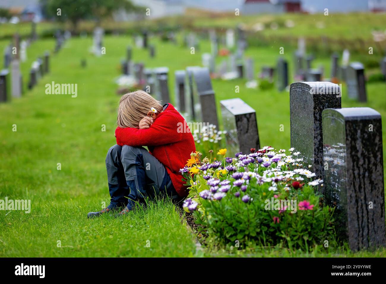 Sad little child, blond boy, standing in the rain on cemetery, sad ...