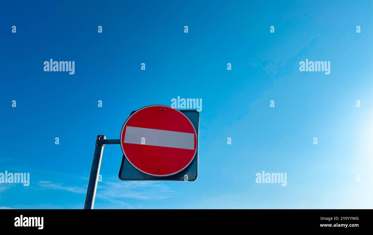 A no-entry road sign against a clear blue sky. The image conveys themes ...