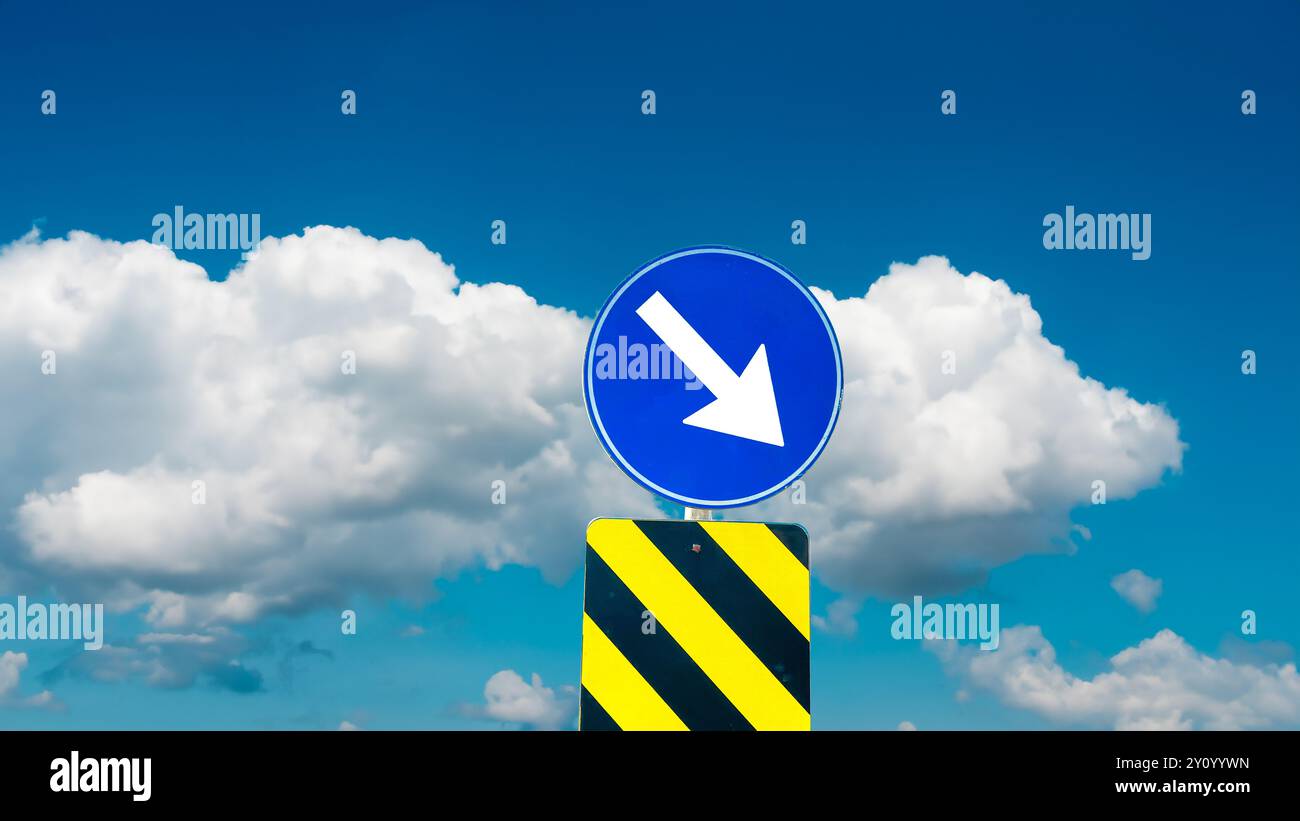 A directional road sign with a white arrow pointing downward, set ...
