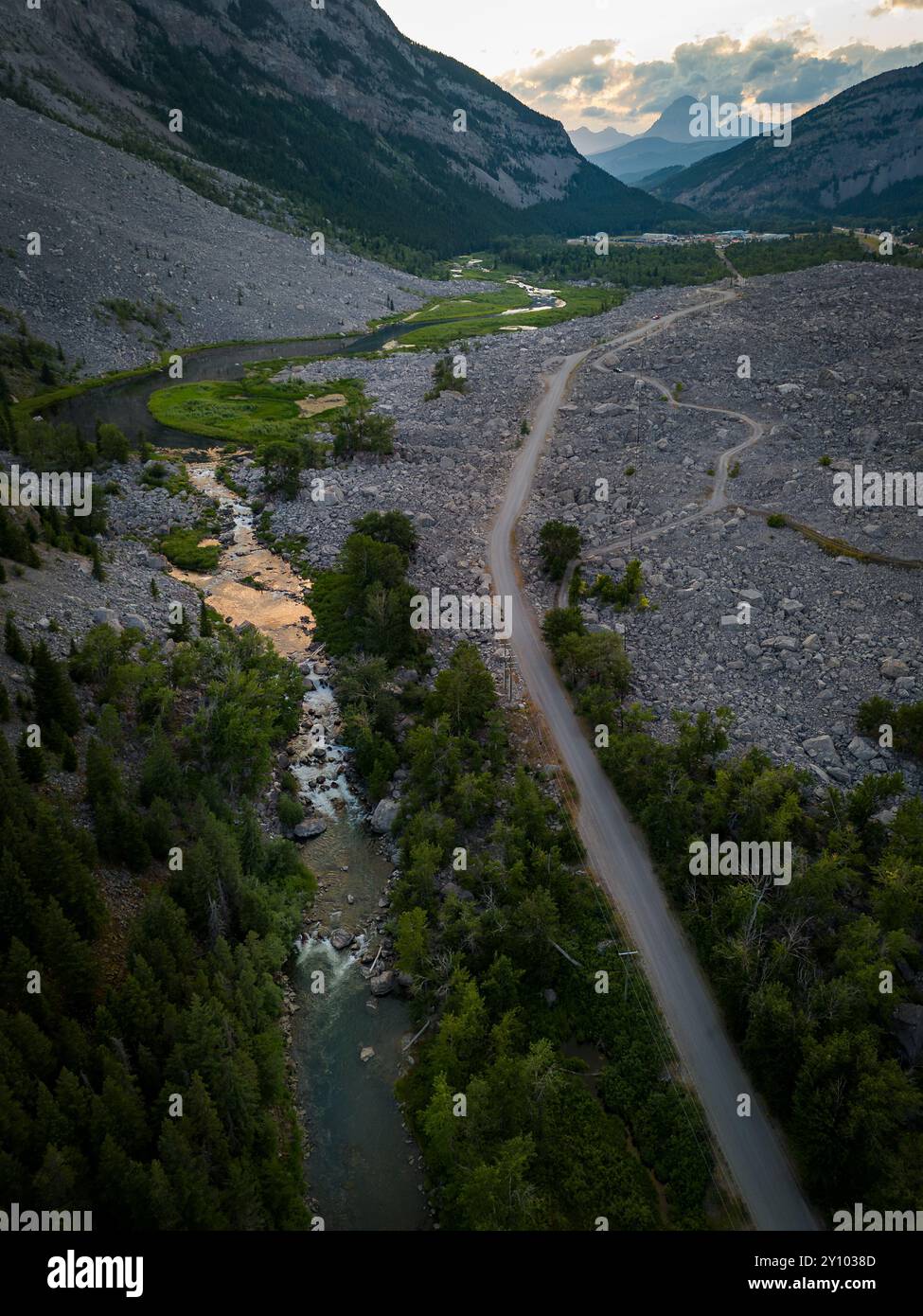 Gravel road parallels a river overlooking the Frank Slide Historic site ...