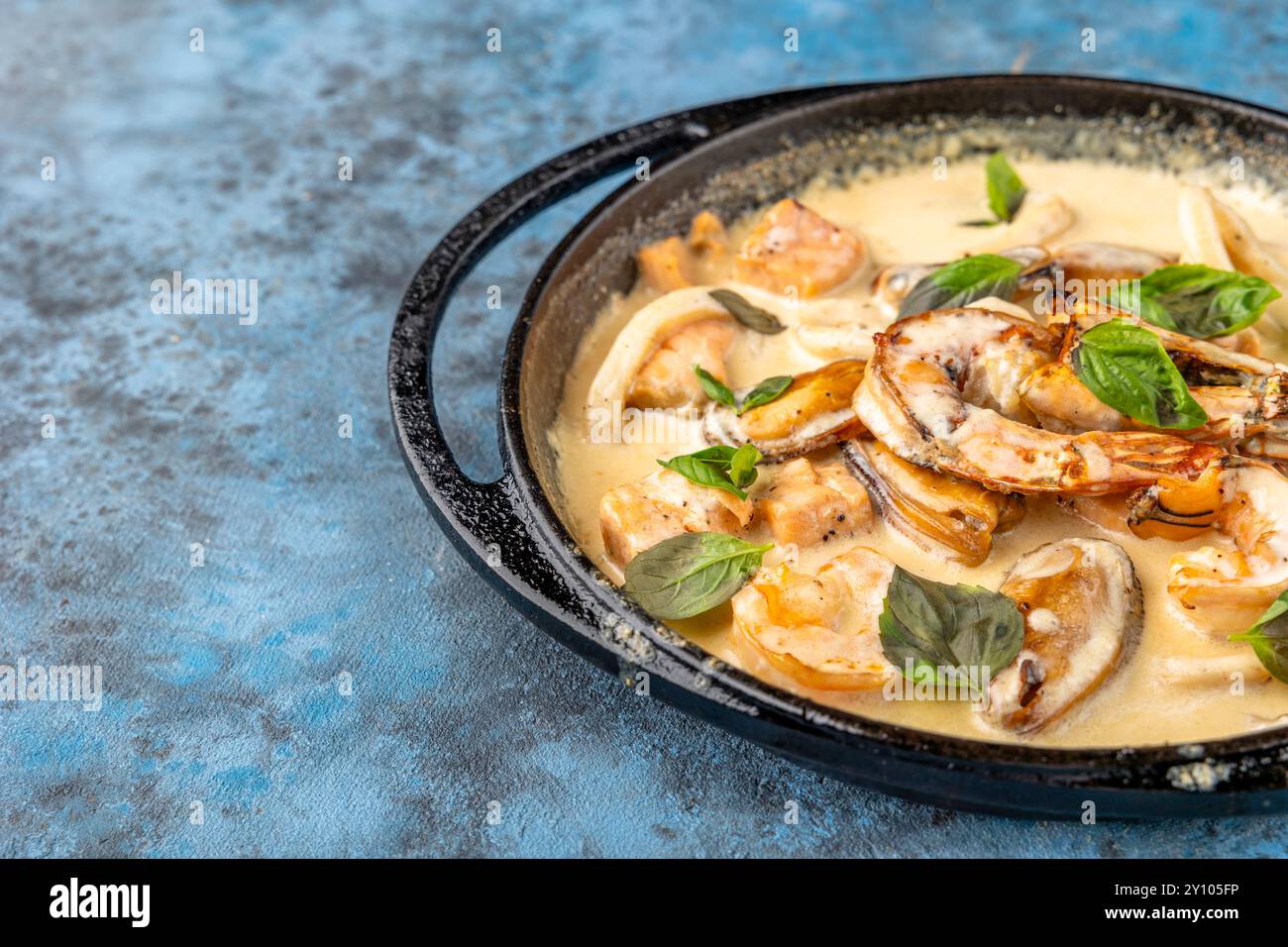Creamy seafood casserole pot shrimps, squid calamari, fish fillet ...
