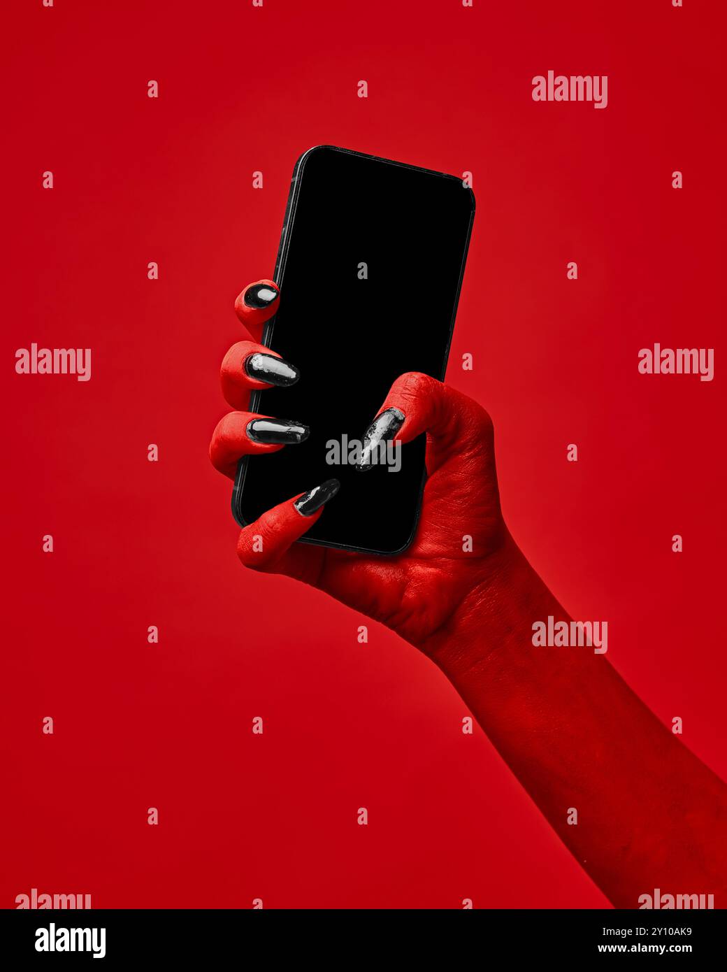 Horror red devil's hand with blank long nails holding smartphone with ...