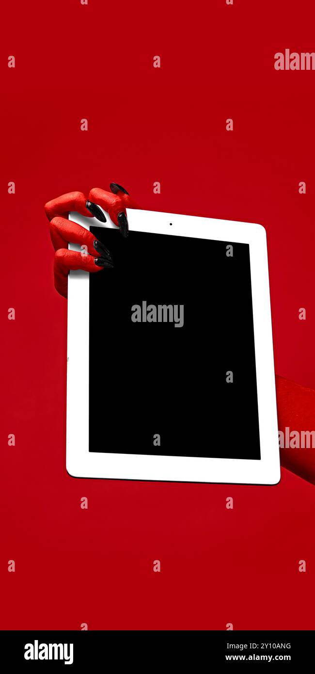 Horror red devil's hand with blank long nails holding tablet with blank ...