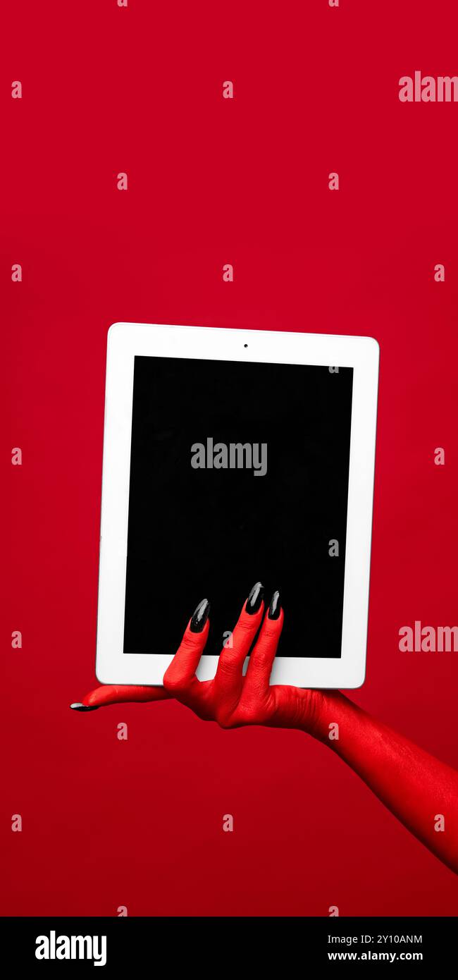 Horror red devil's hand with blank long nails holding tablet with blank ...