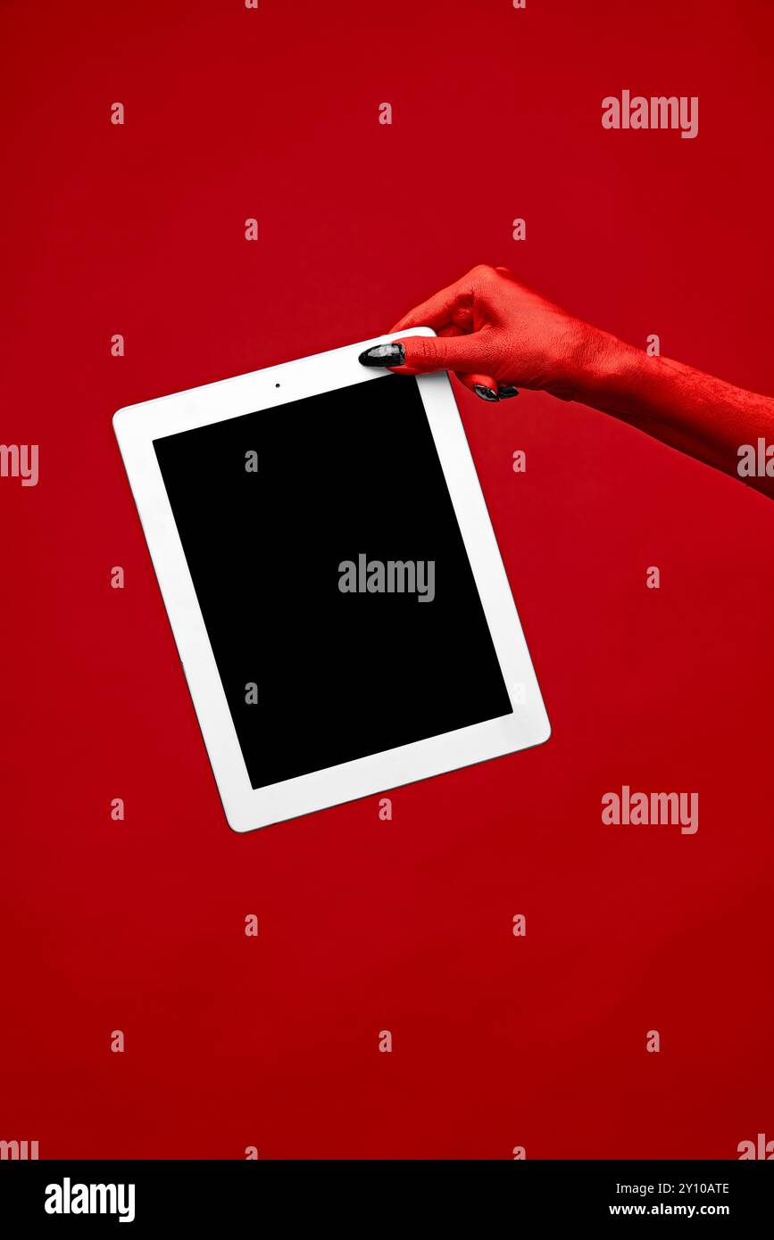 Horror red devil's hand with blank long nails holding tablet with blank ...