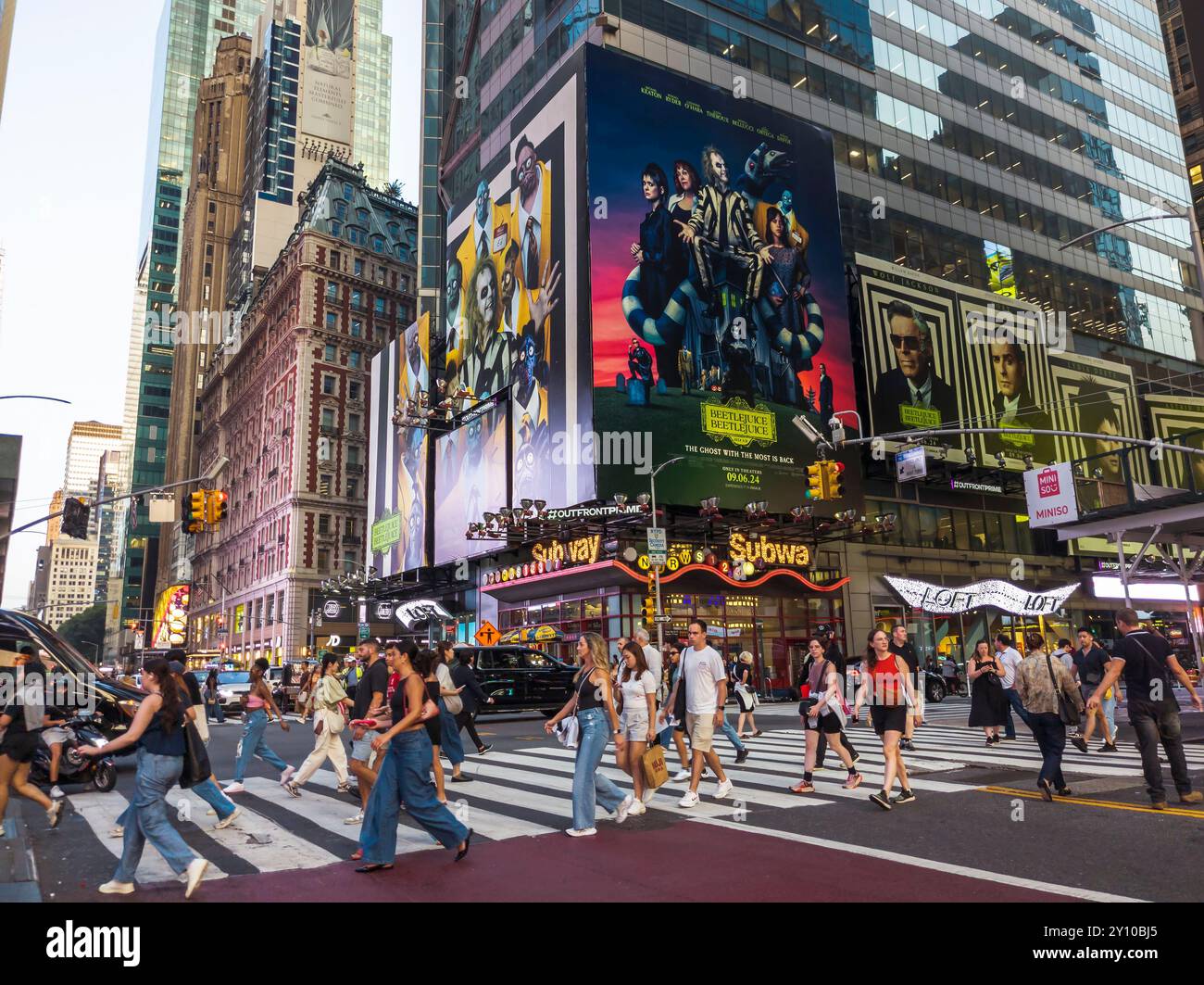 Hordes of people cross West 42nd Street under advertising for the ...