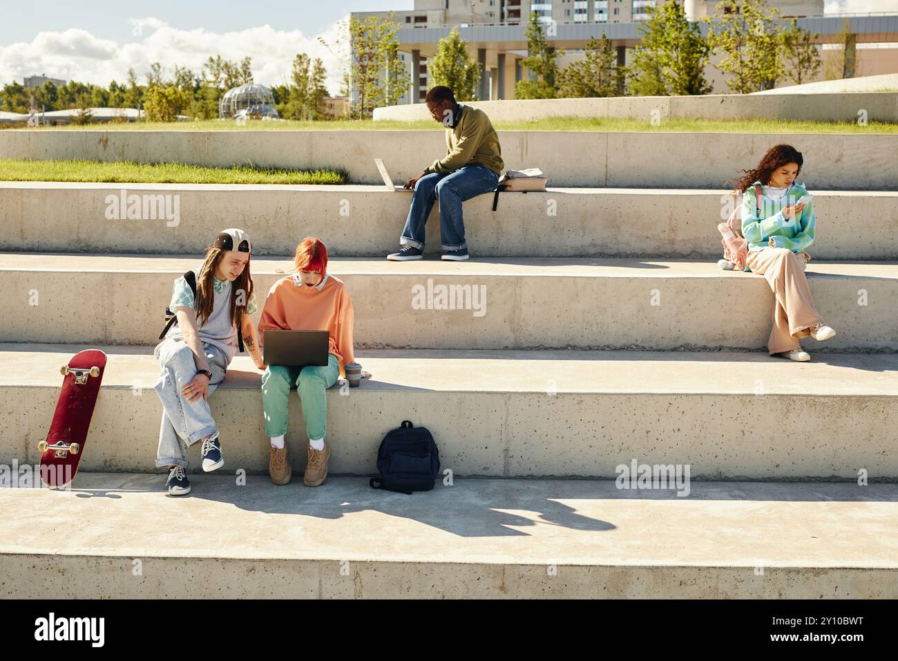 Wide angle shot of students of diverse ethnicity sitting on concrete ...