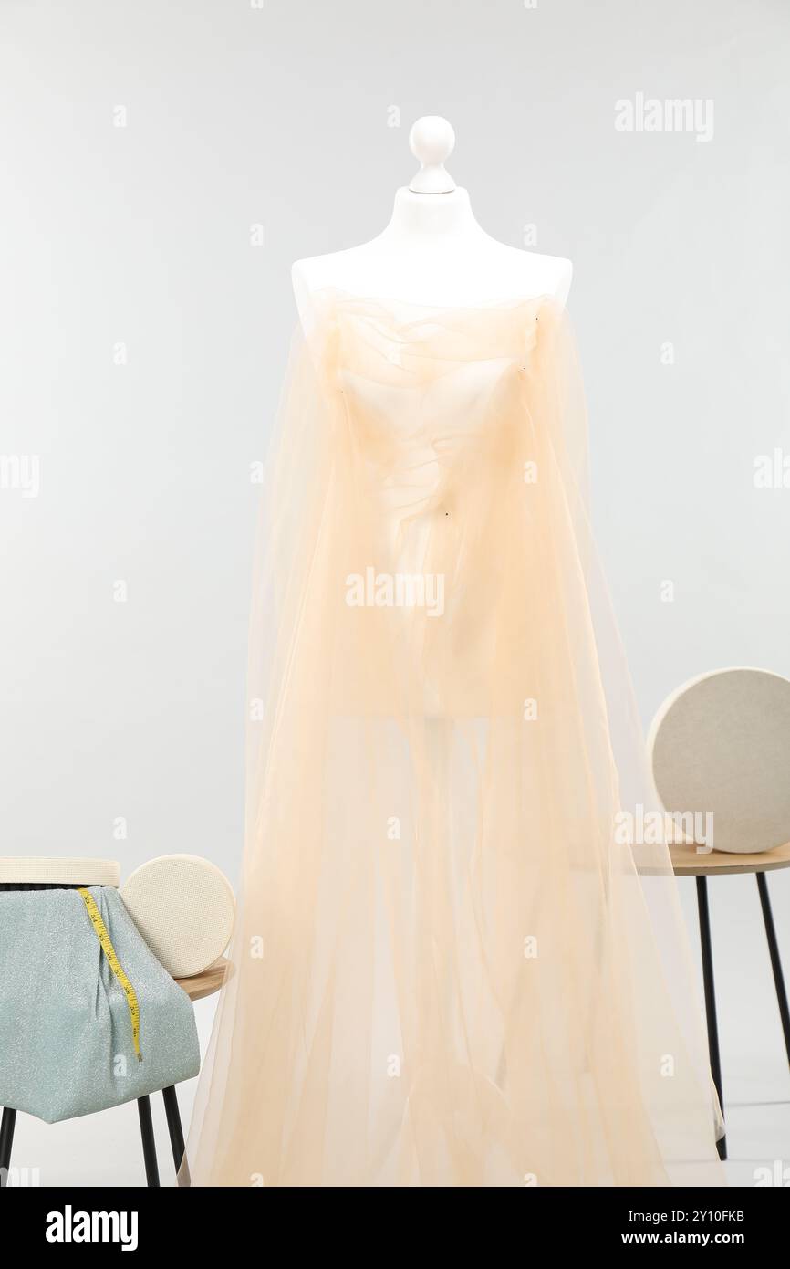 Mannequin with fabric and boxes on side tables against light grey ...