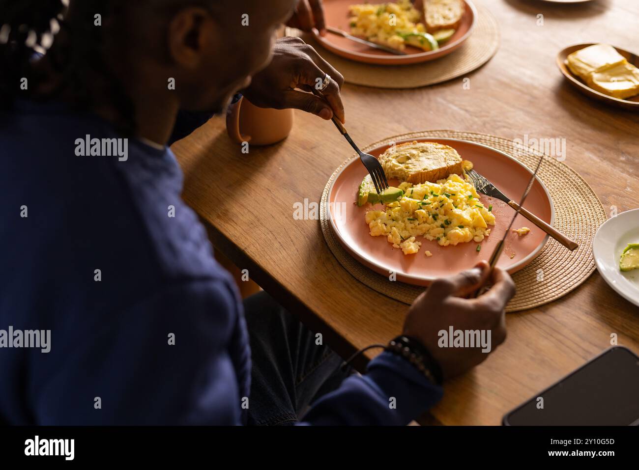Eating breakfast, African American man enjoying scrambled eggs and ...