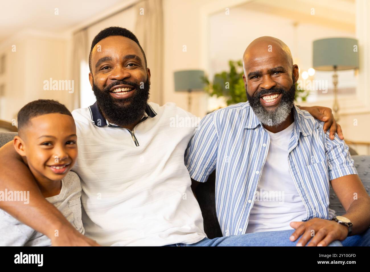 Smiling family of three generations sitting together on couch at home ...