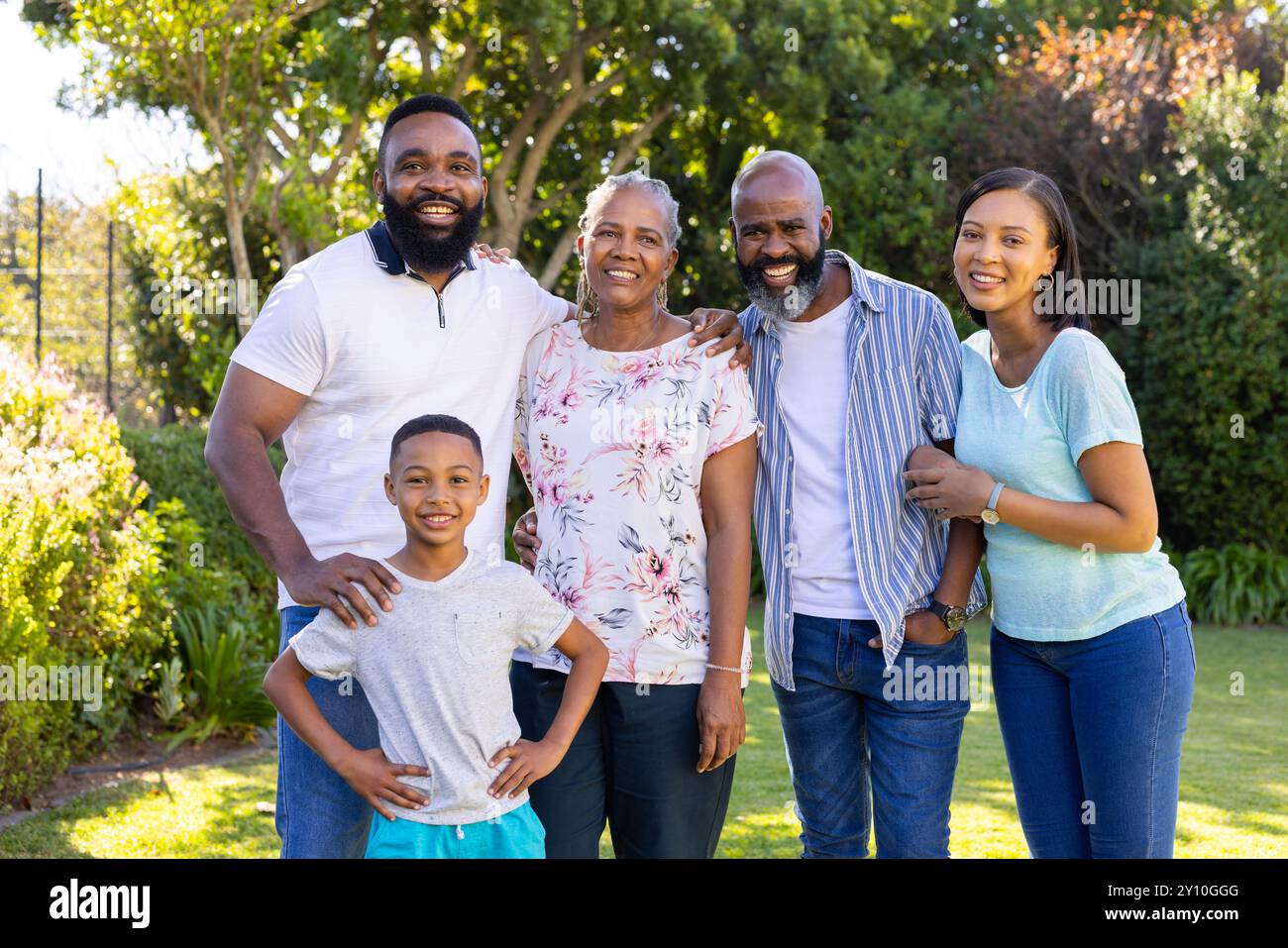 Smiling family of five standing together in garden, enjoying outdoor ...
