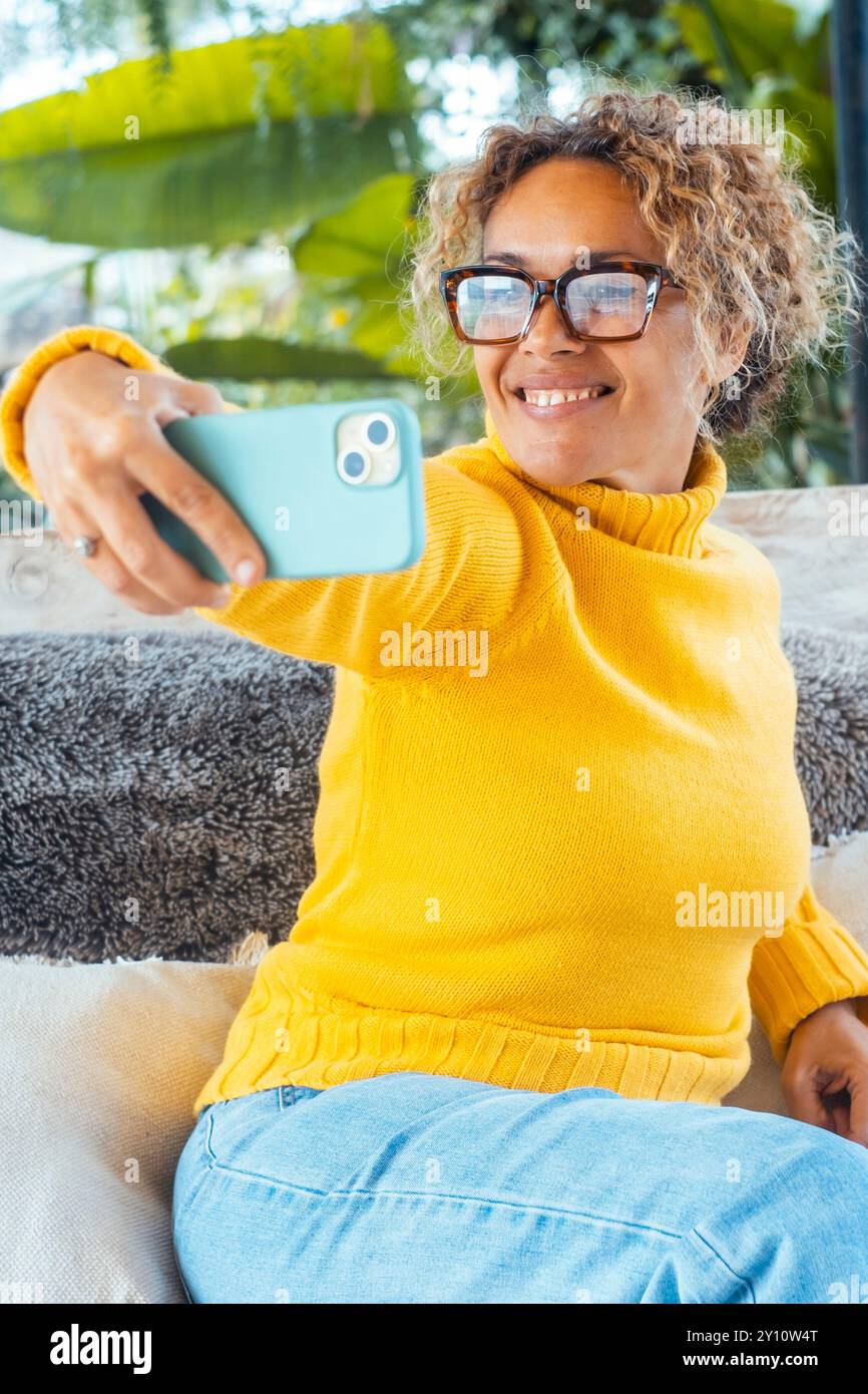 A woman uses her cell phone and relaxes alone in the garden sitting on ...