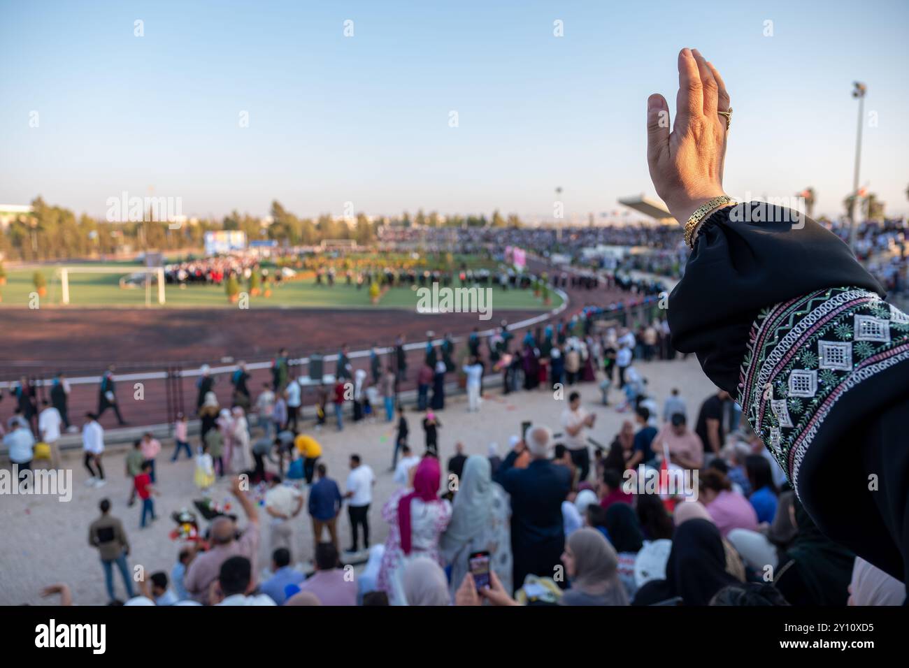 Arabic female watching her son graduation and waving for him while ... Arabic female watching her son graduation and waving for him while ...