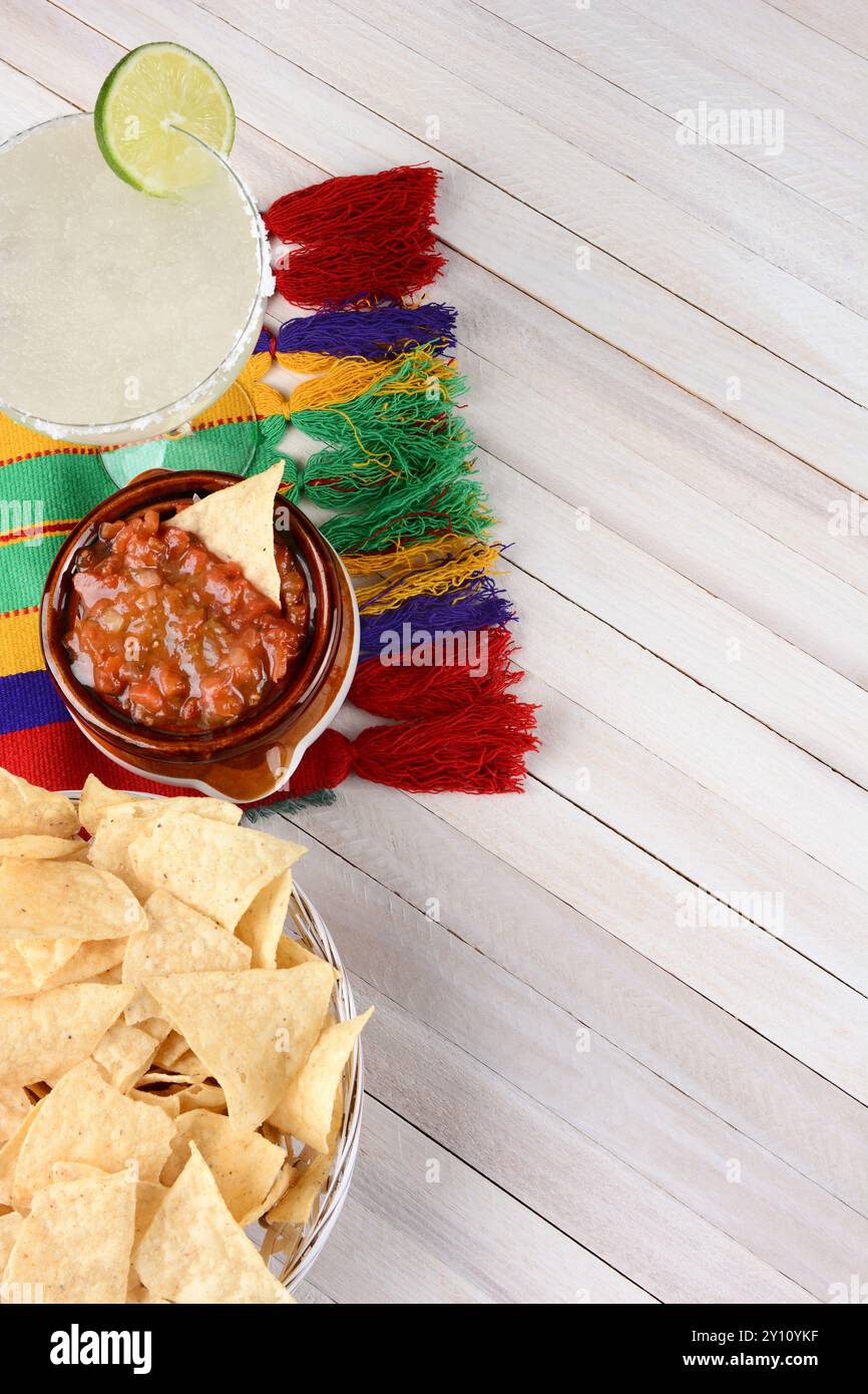 Overhead view of a margarita cocktail with chips and salsa on a white ...