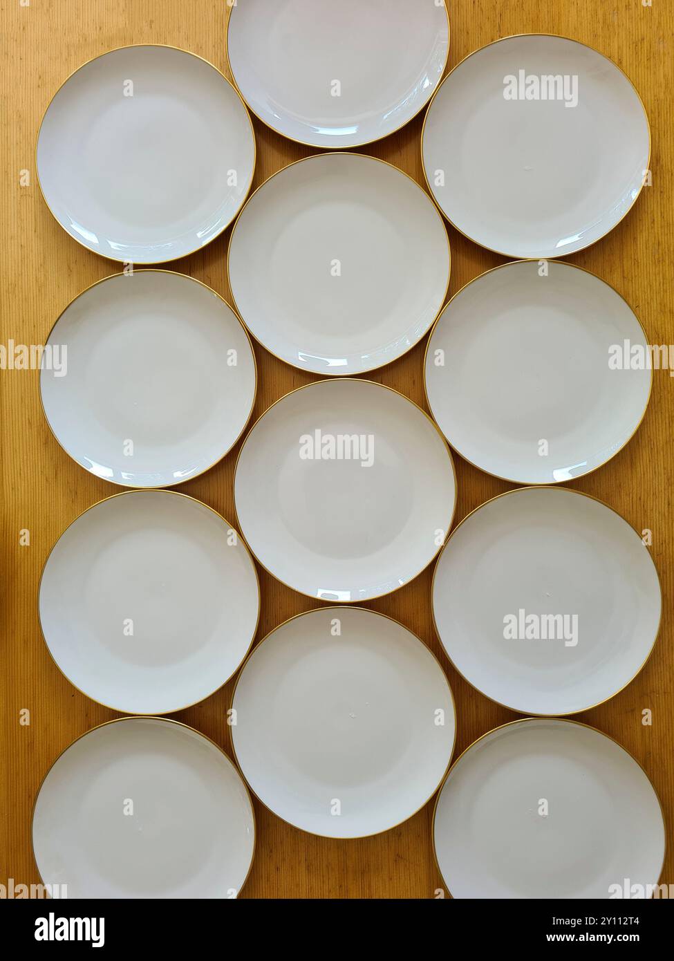 White empty dinner plates arranged next to each other on a wooden table ...