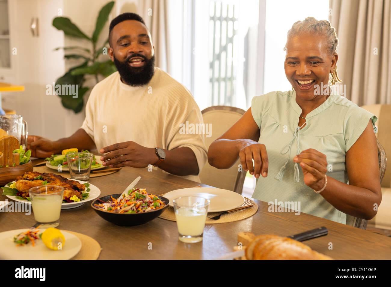 Enjoying multigenerational family meal, smiling man and woman sitting ...