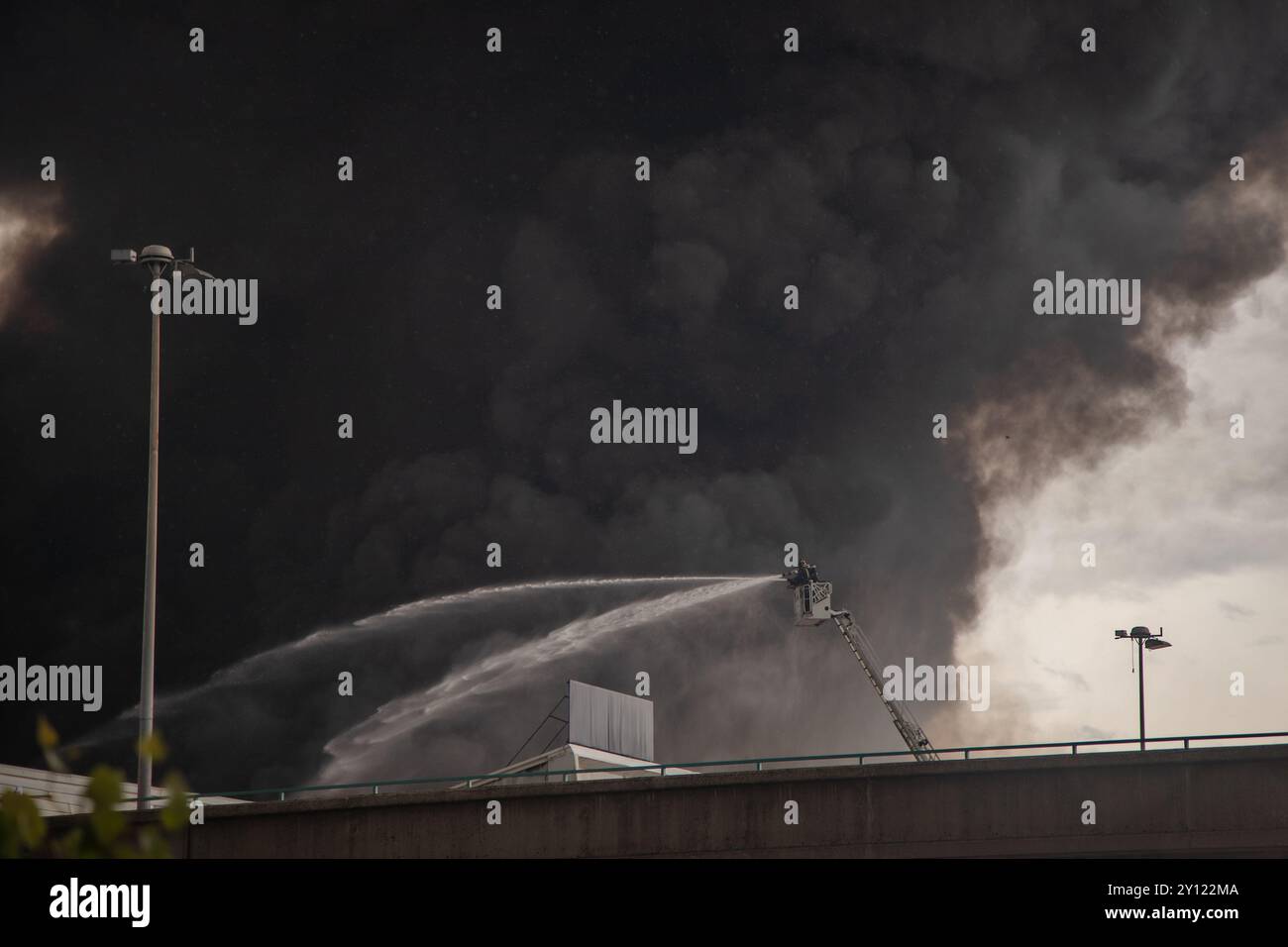 A firefighter sprays water from a hydraulic ladder to extinguish a ...