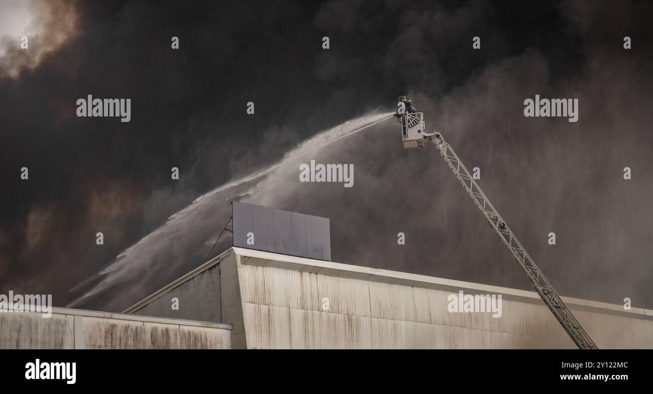 A Firefighter Sprays Water From A Hydraulic Ladder To Extinguish A