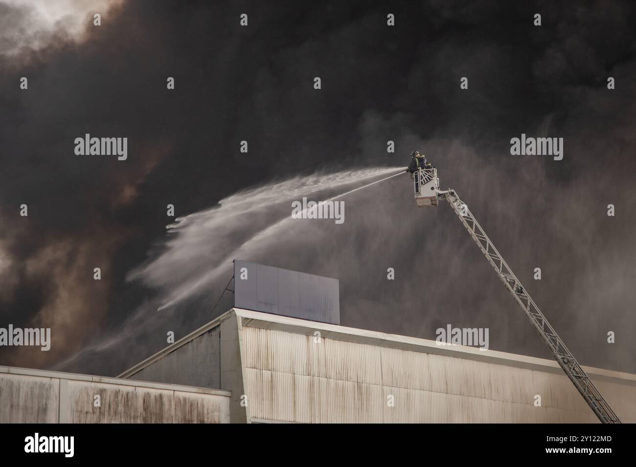 A firefighter sprays water from a hydraulic ladder to extinguish a ...