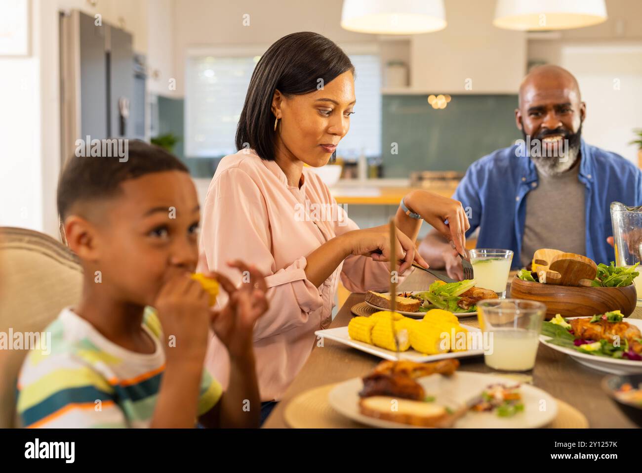 multigenerational family enjoying meal together, eating corn and salad ...