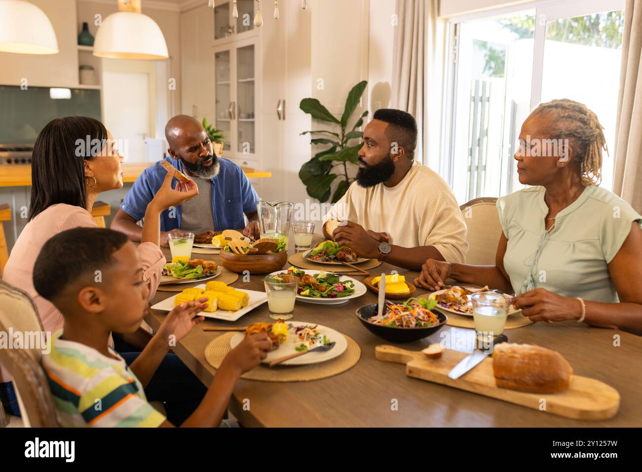multigenerational family enjoying meal together, sitting around dining ...