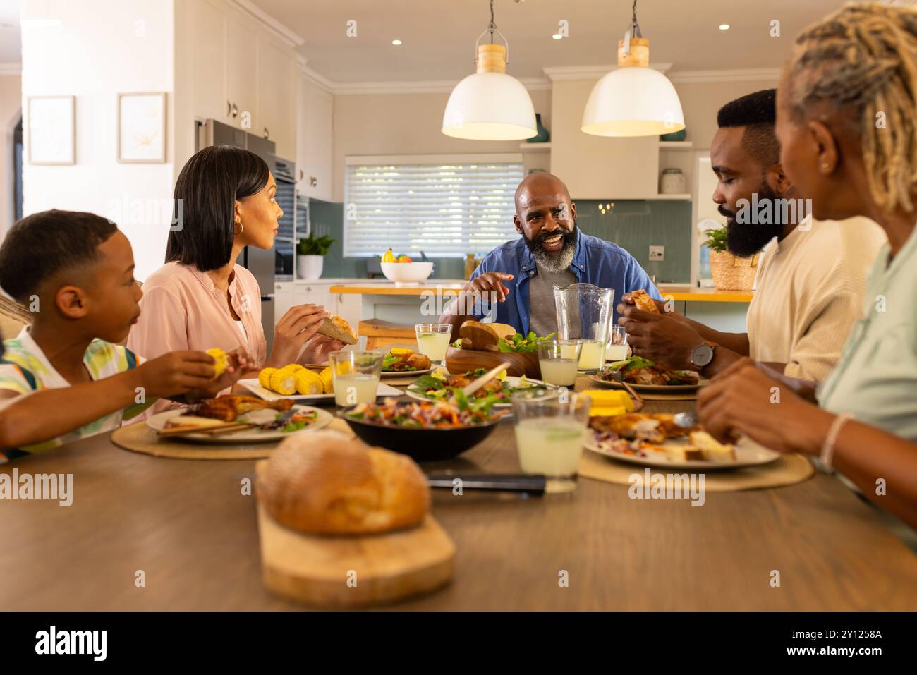 multigenerational family enjoying dinner together, sharing stories and ...