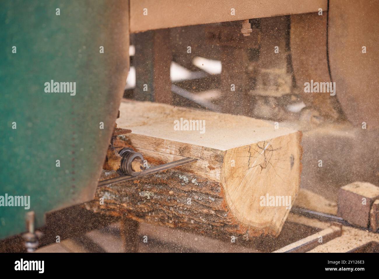 A close-up view of a sawmill with a large log being cut by a band saw ...