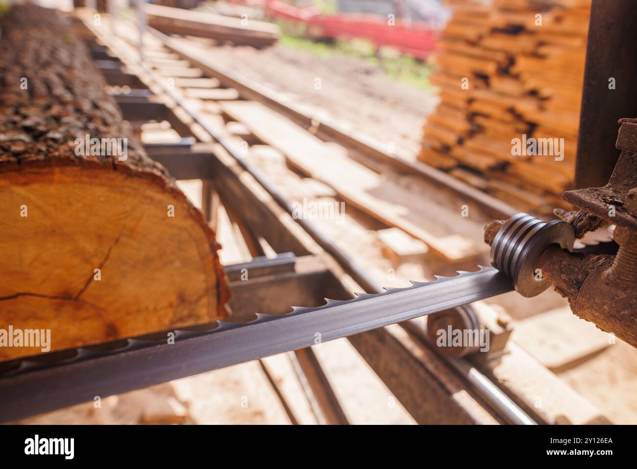 A close-up view of a sawmill with a large log being cut by a band saw ...