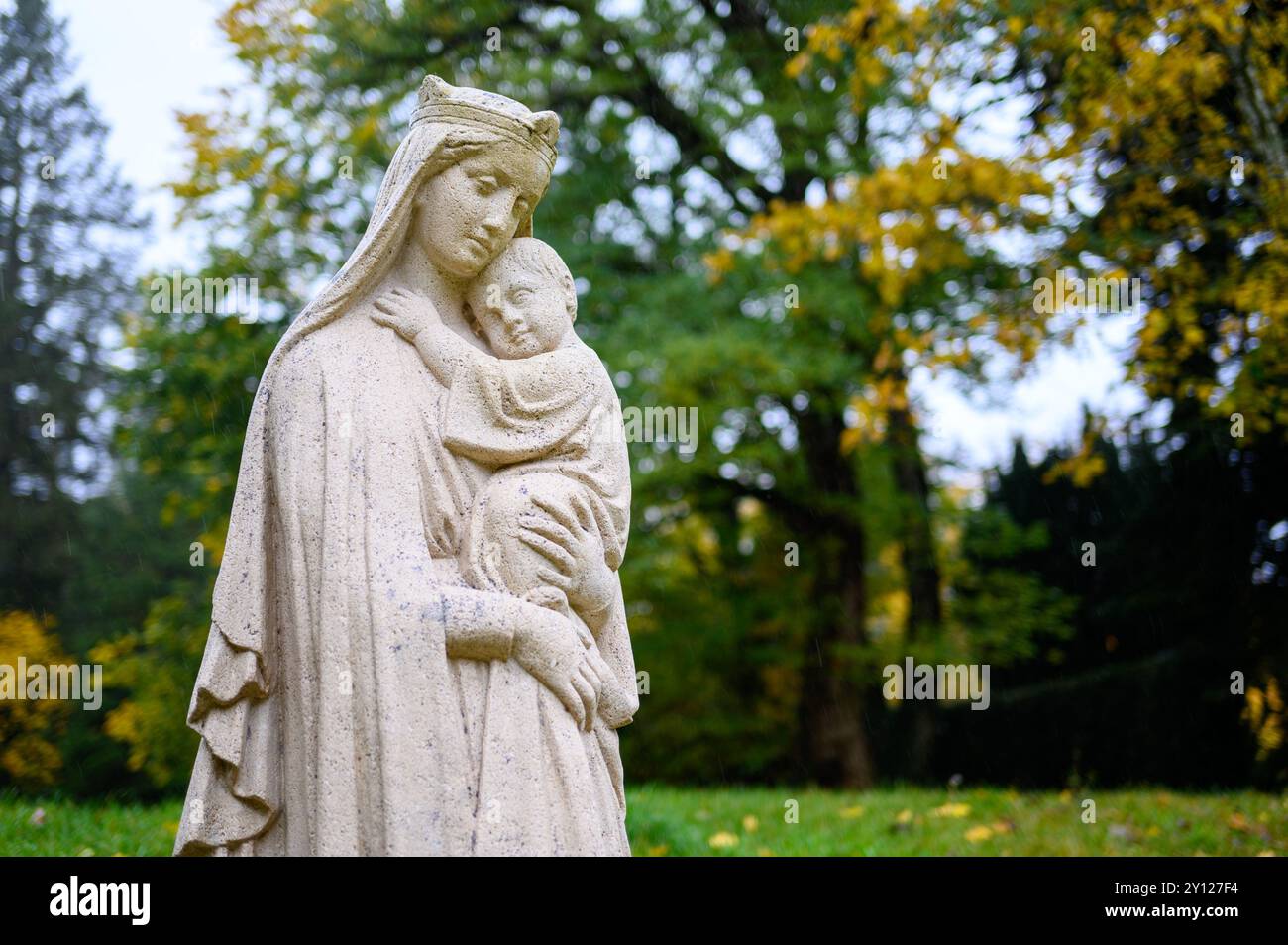 A statue of the Virgin Mary with the Infant Jesus in the park of the ...