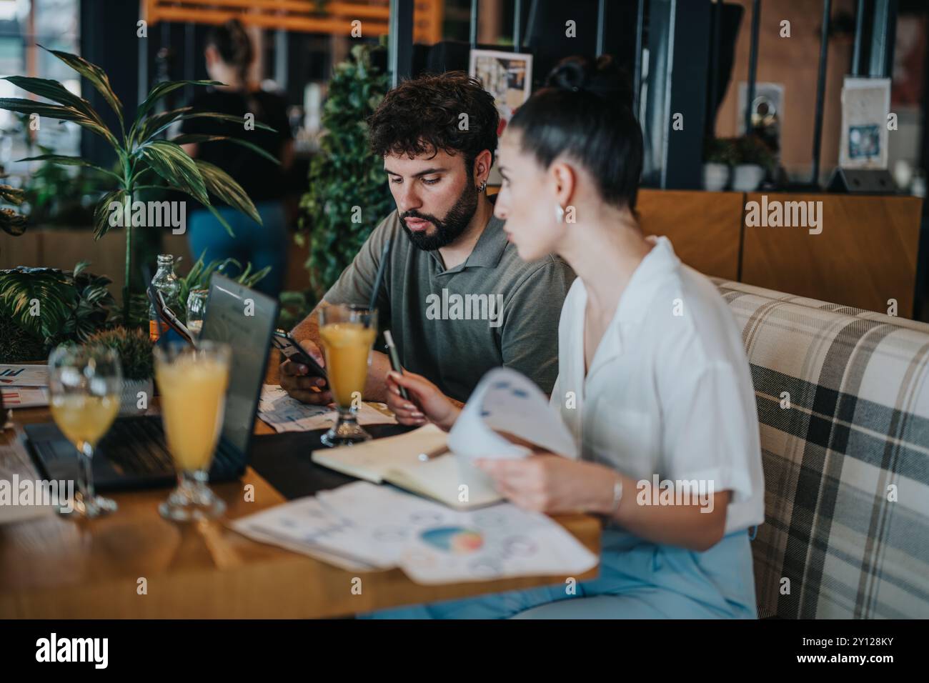 Businesspeople having a meeting in a coffee bar with laptops, documents ...