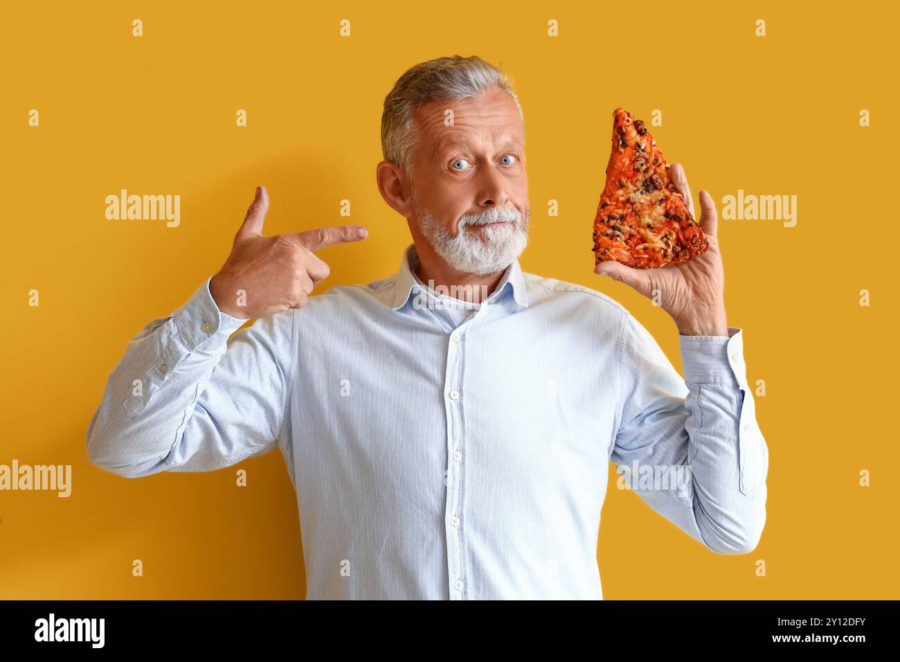 Mature man pointing at tasty pizza on yellow background Stock Photo - Alamy