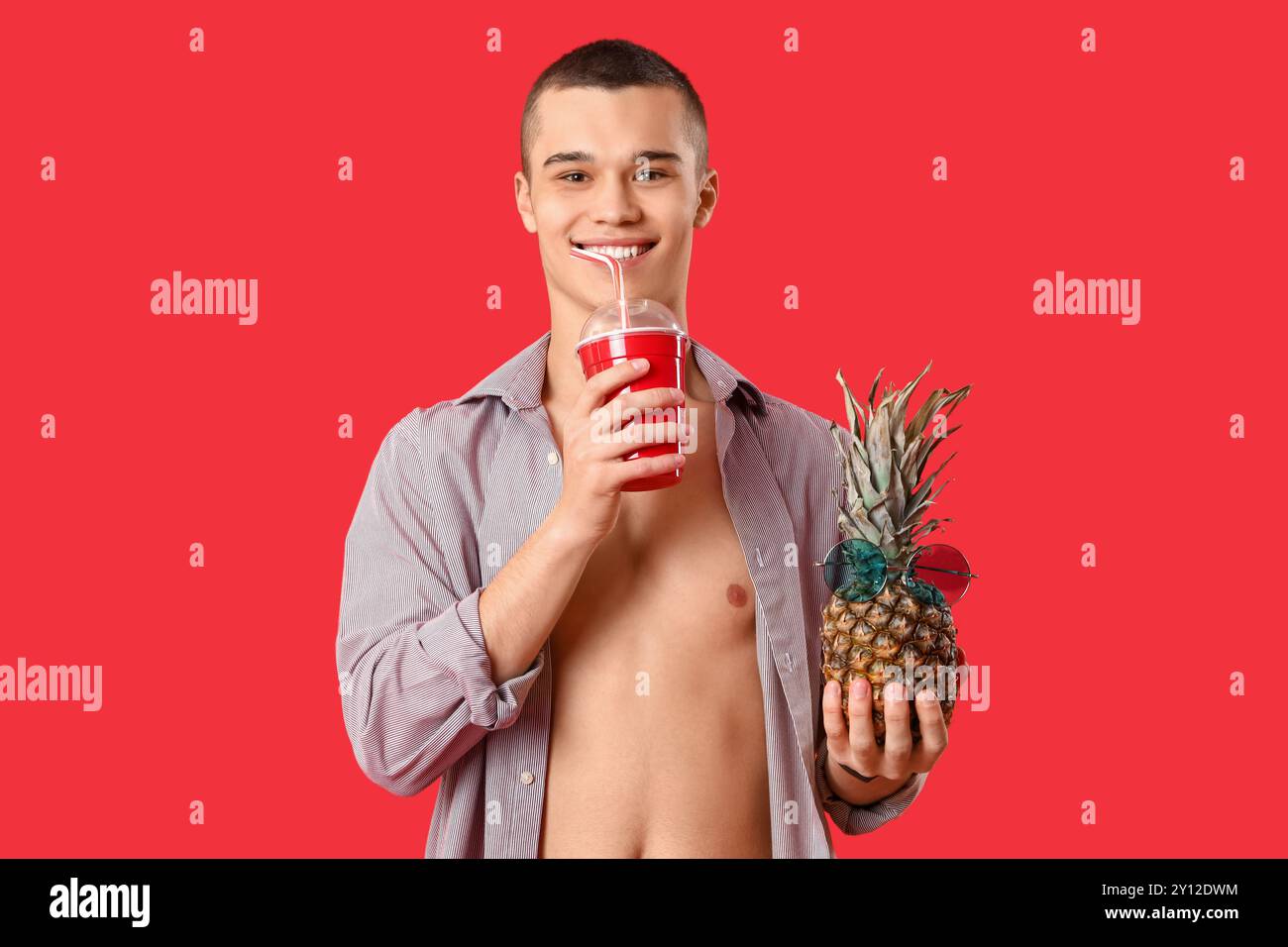 Teenage boy with cup of soda and pineapple on red background Stock ...