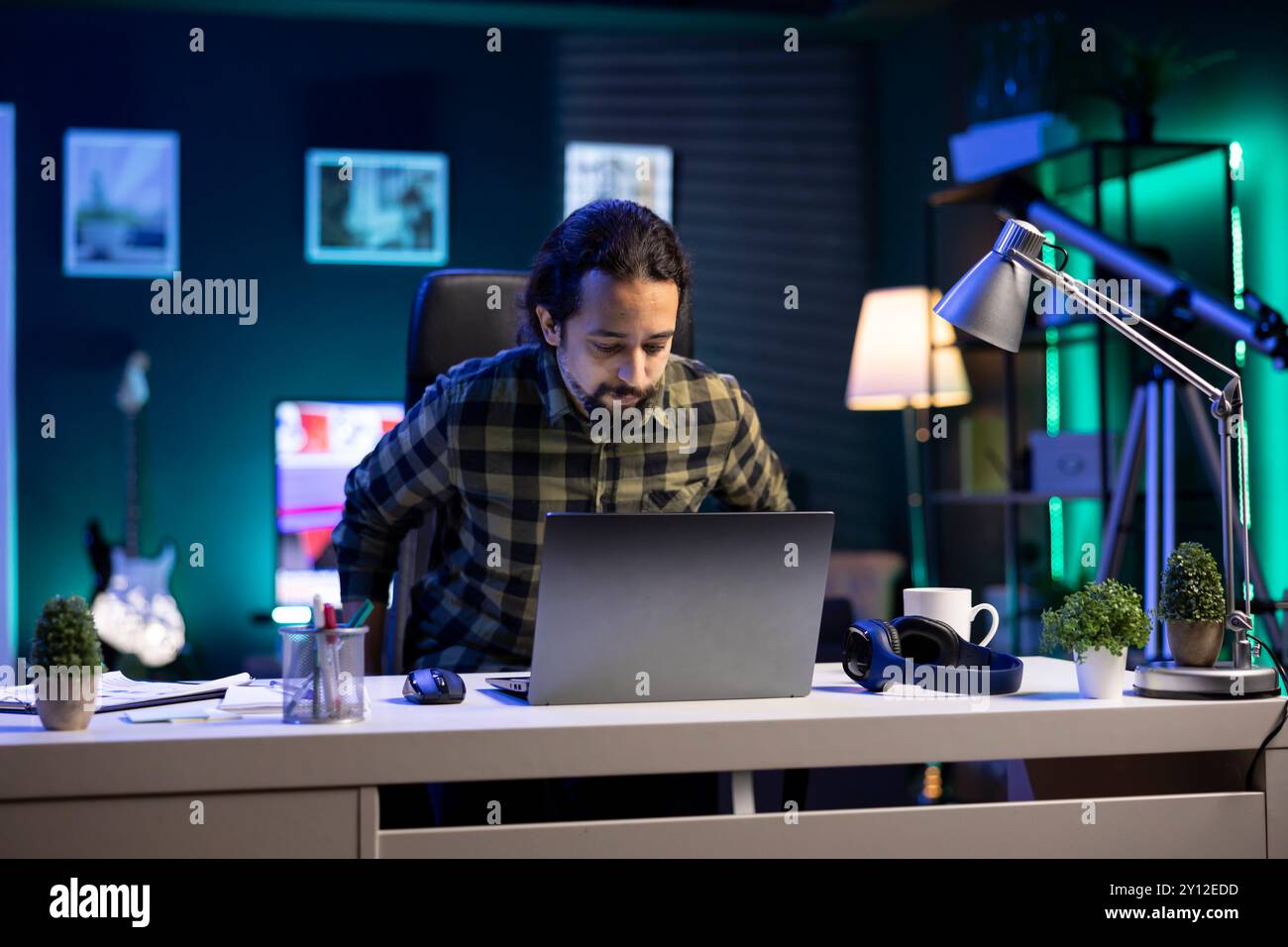 Working indoors, a tech-savvy man sits at a table, easily demonstrating ...