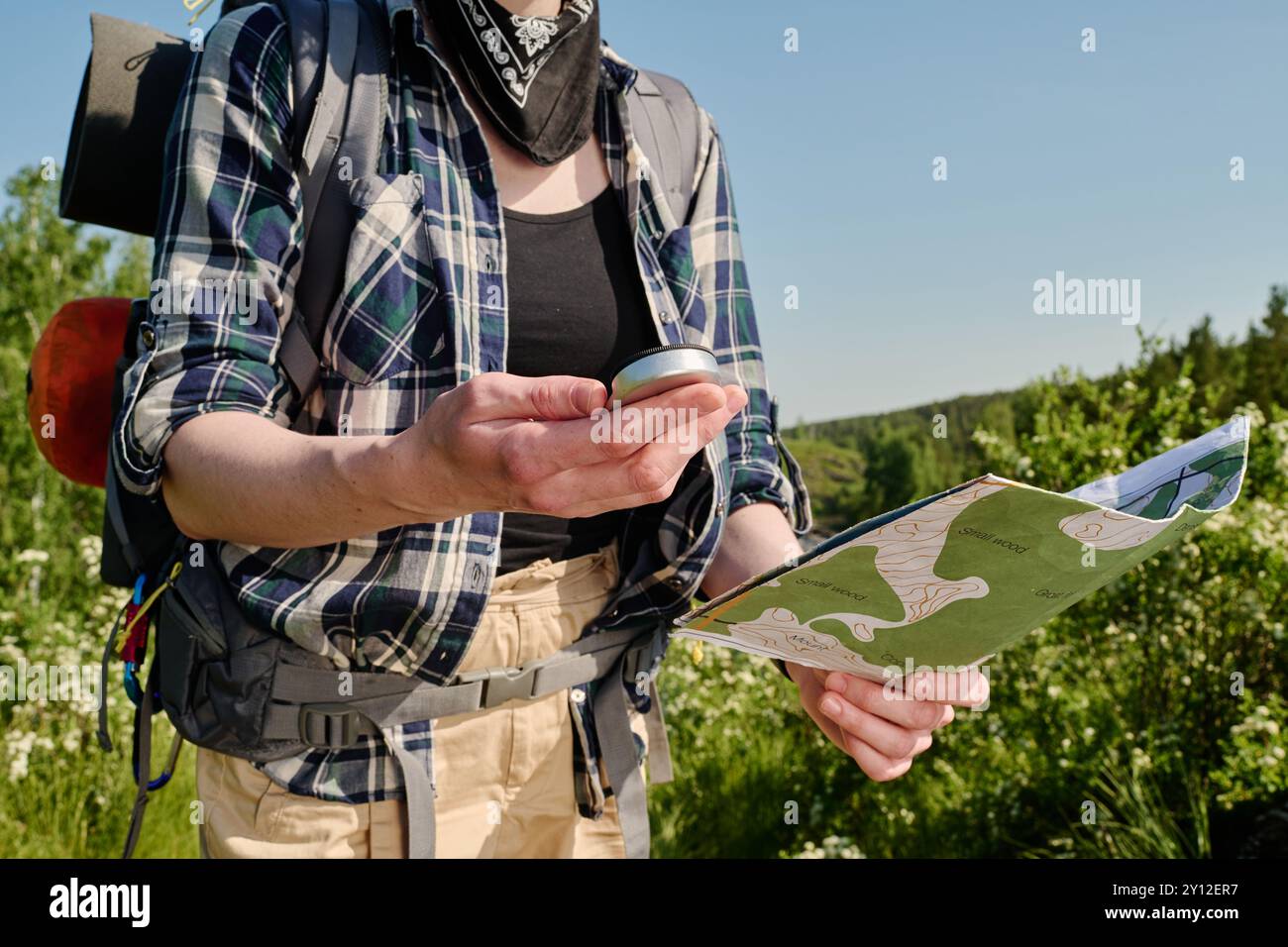 Hands of young unrecognizable female hiker with compass and unfolded ...
