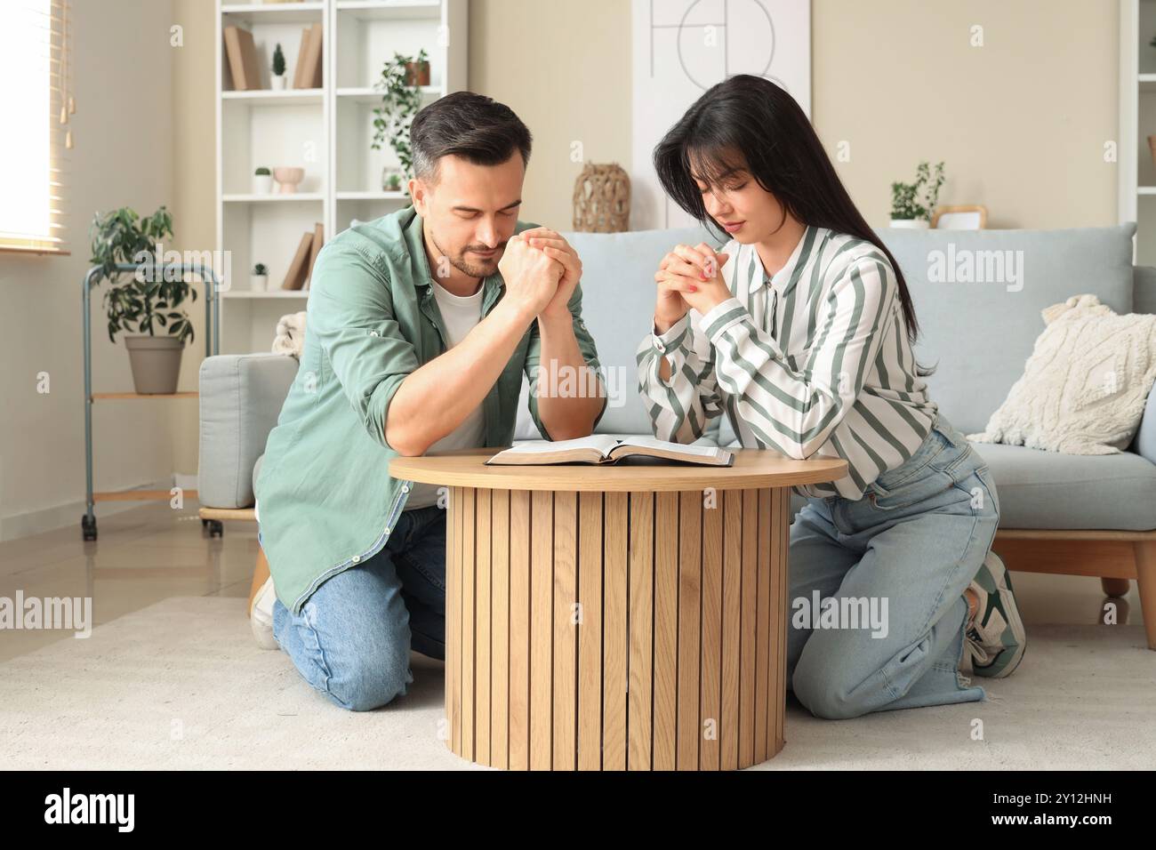 Religious couple with Holy Bible praying at home Stock Photo - Alamy