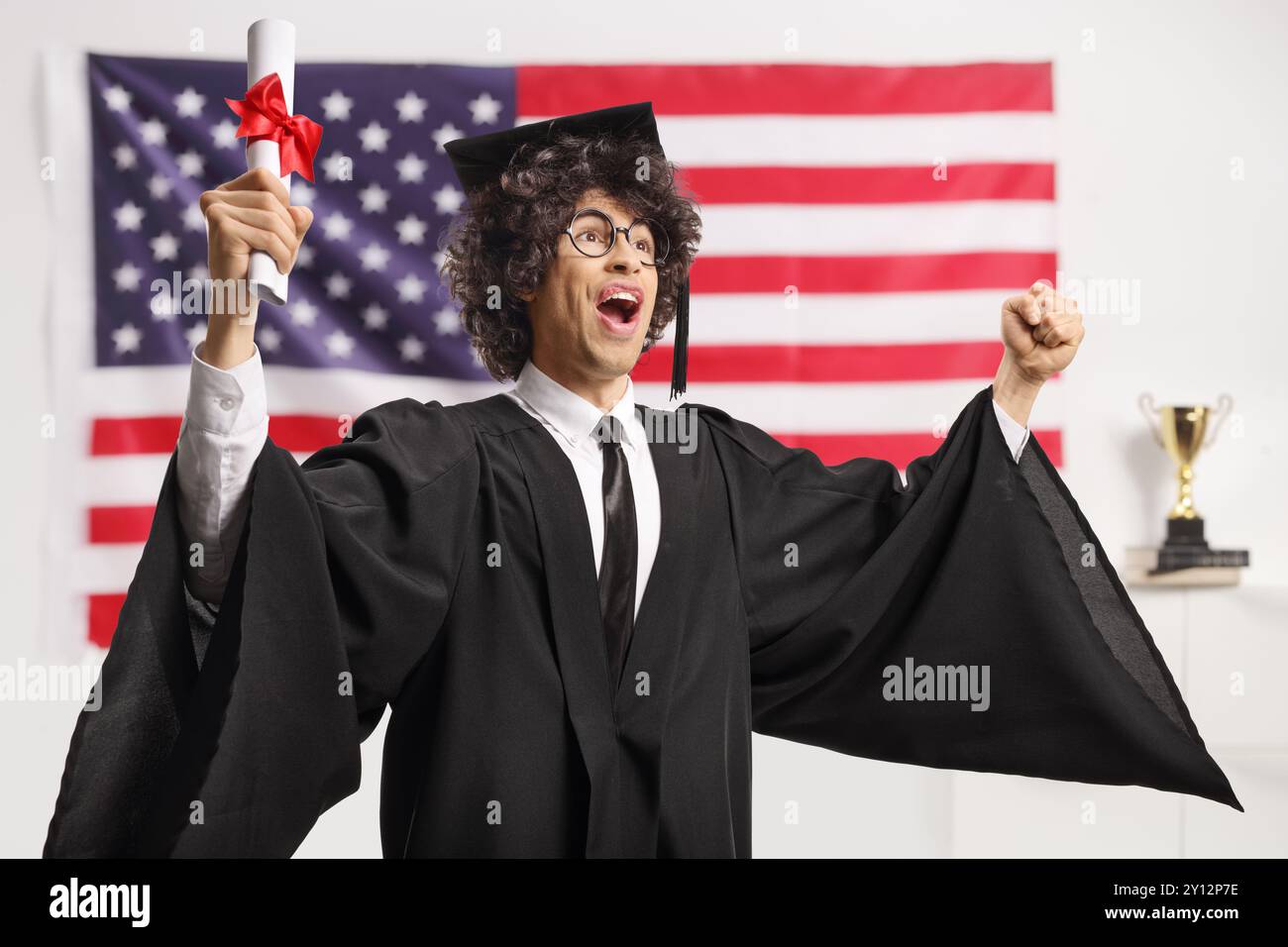 Happy graduate student holding diploma in front of USA flag Stock Photo ...