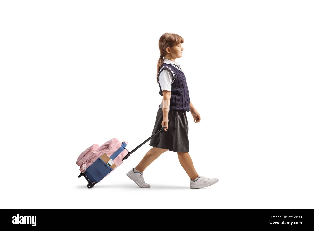 Schoolgirl walking and pulling a backpack isolated on white background ...