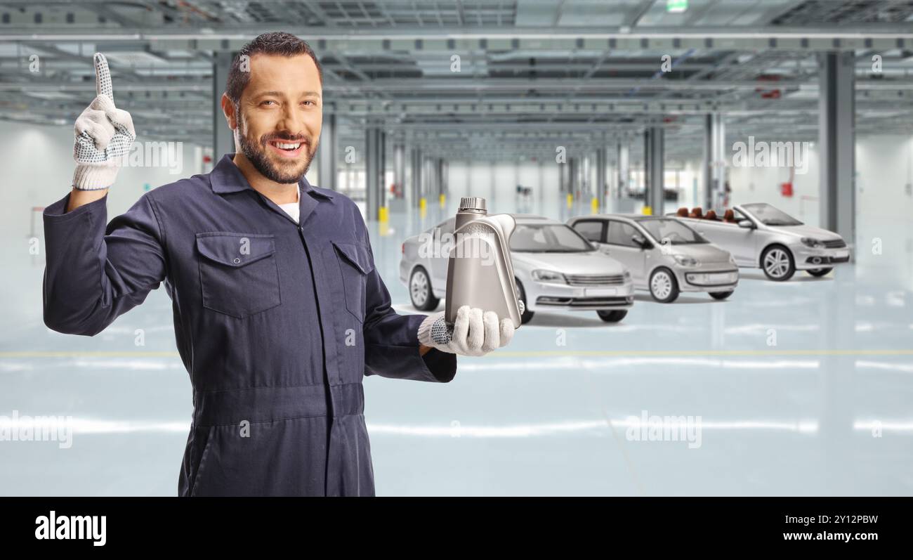 Car mechanic holding an engine oil plastic bottle and pointing up ...