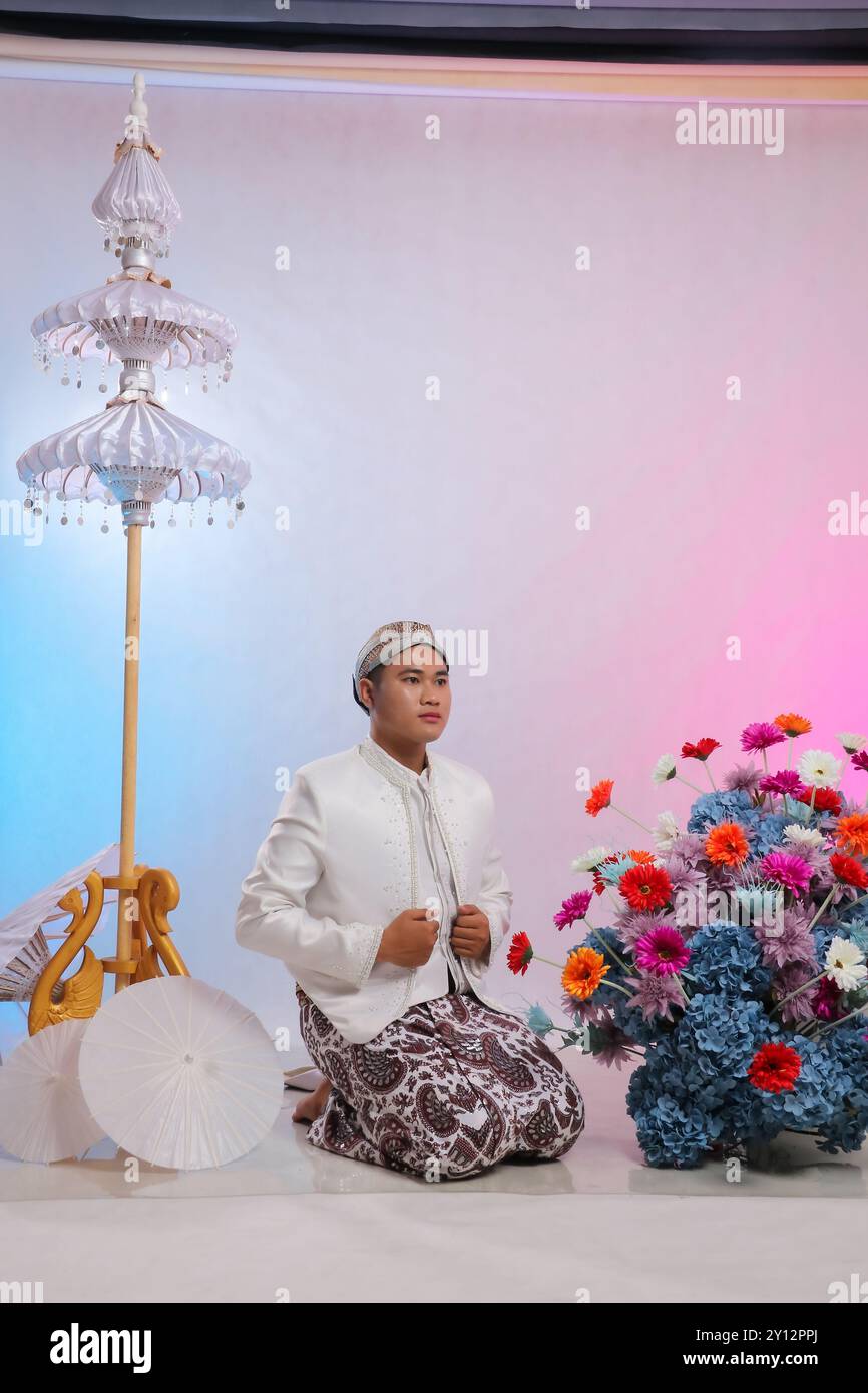 Full body, elegant adult indonesia man sitting on the floor candidly ...