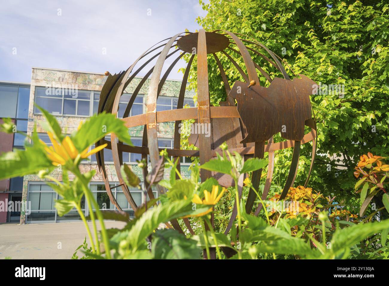 Metal globe sculpture surrounded by plants in front of a modern ...